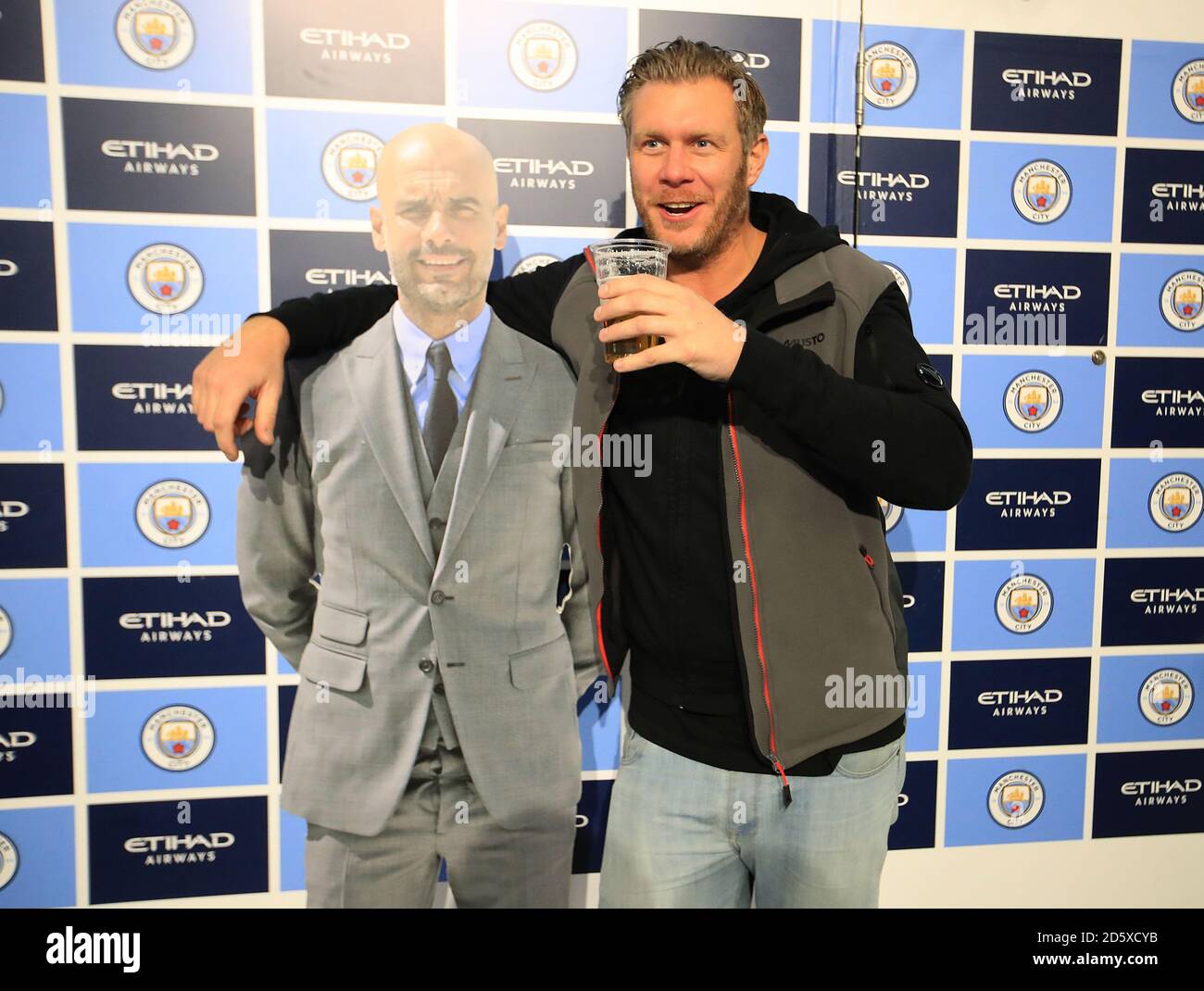 A fan poses with a cardboard cut-out of Manchester City manager Pep ...