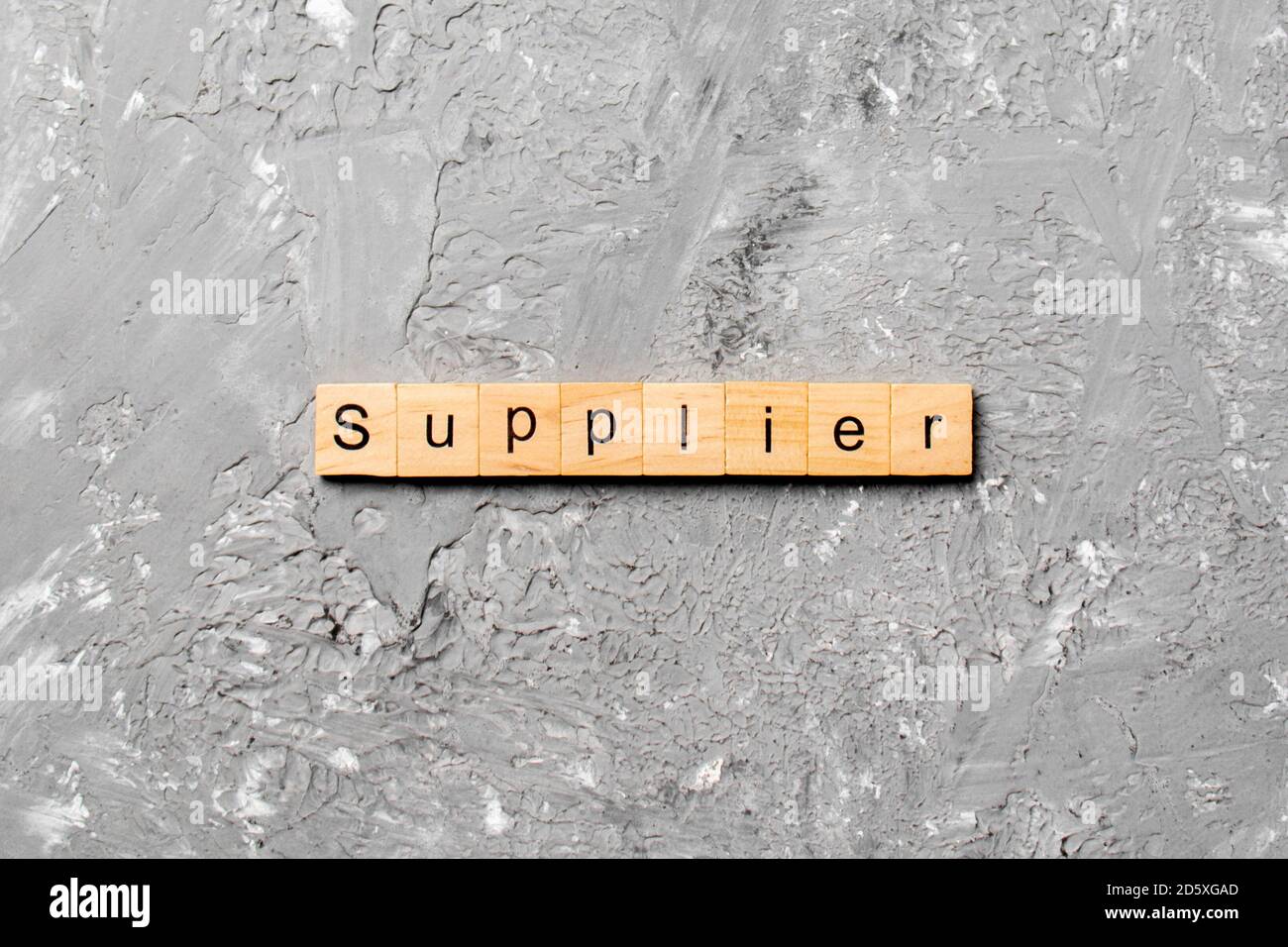 SUPPLIER word written on wood block. SUPPLIER text on cement table for ...