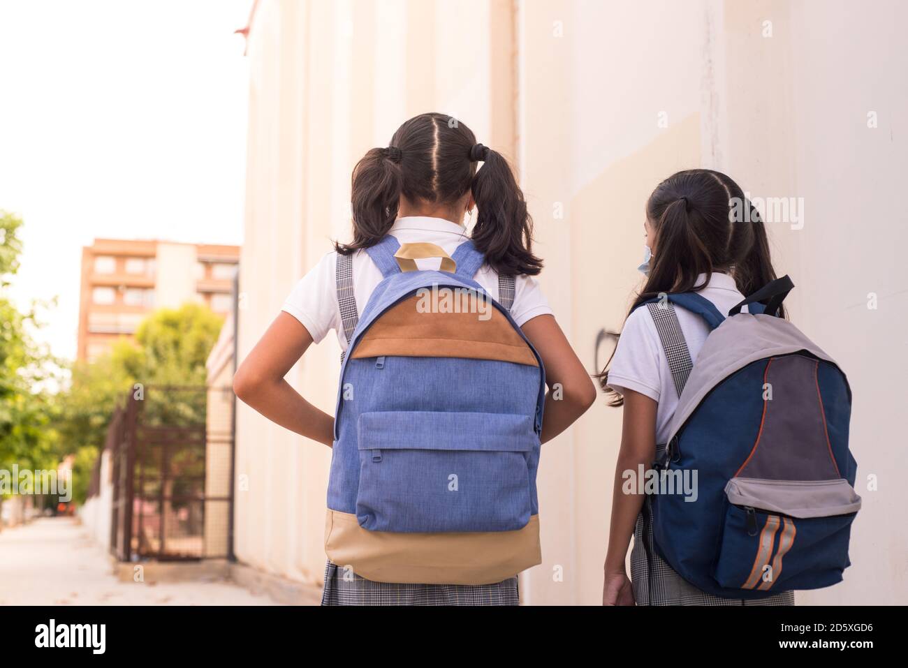 Two little girls on rear view wearing backpacks on school, primary back ...