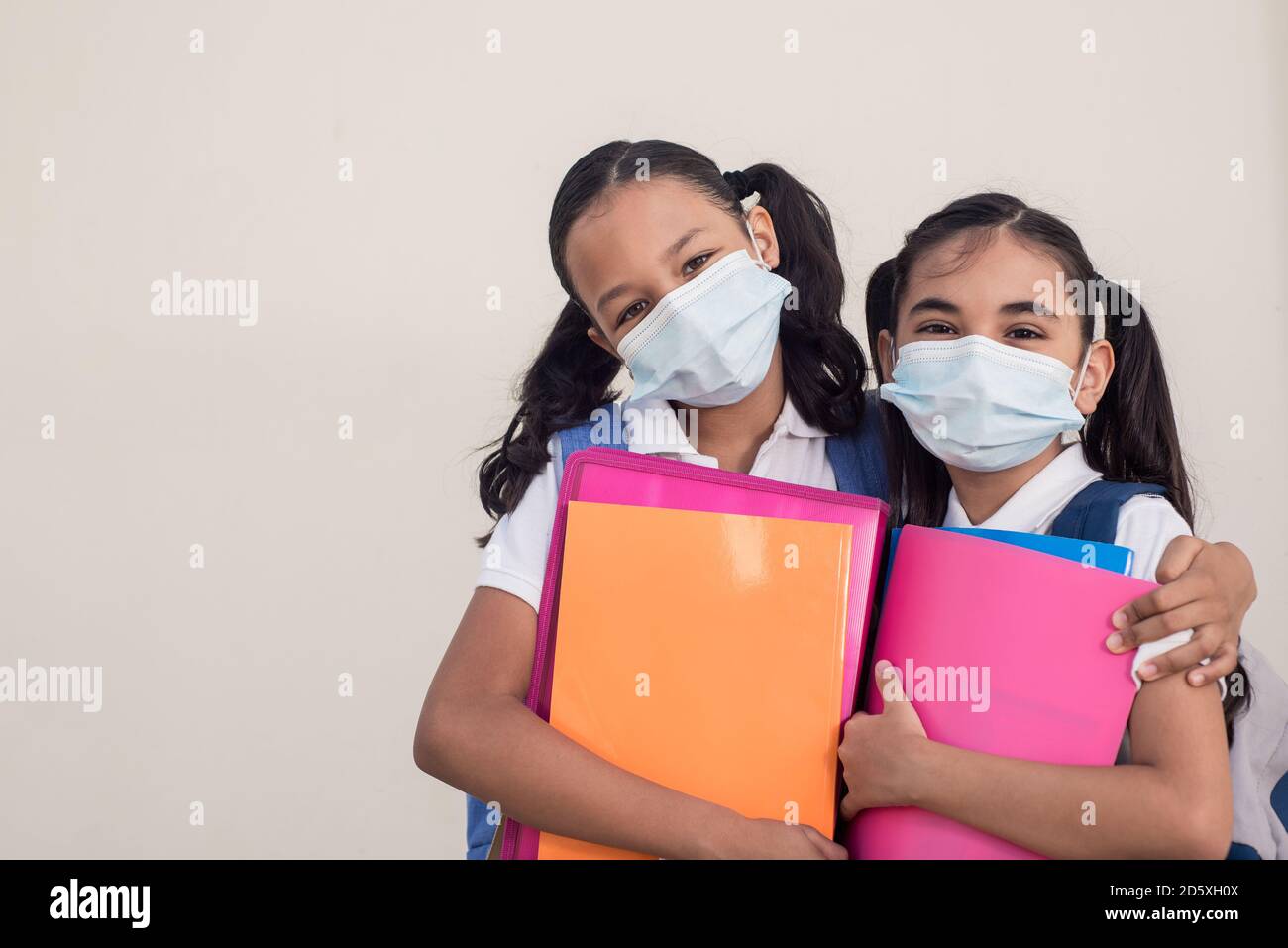 Cute little girls of primary hug each other with the mask on. school ...