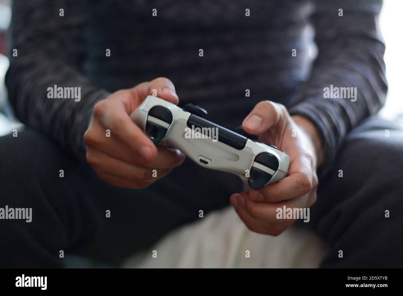 A man holding a game controller. A young man playing video games Stock ...