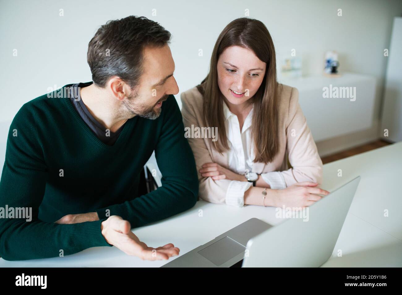 Businessman and employee using laptop at desk in office Stock Photo - Alamy