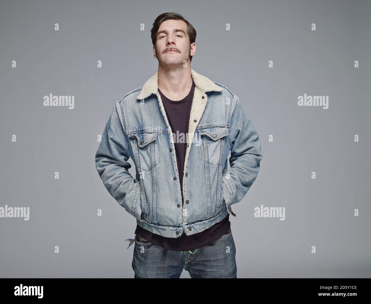 Portrait of man wearing jeans jacket in front of grey background Stock ...