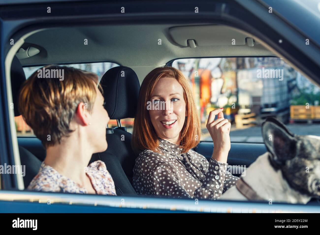 Two female friends sitting in their car talking together Stock Photo ...