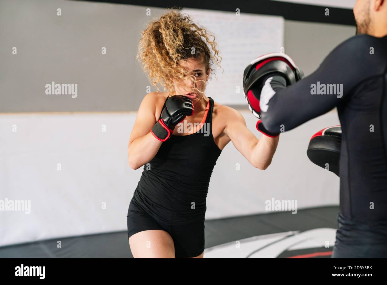 female boxer training with her highly concentrated trainer wearing red ...