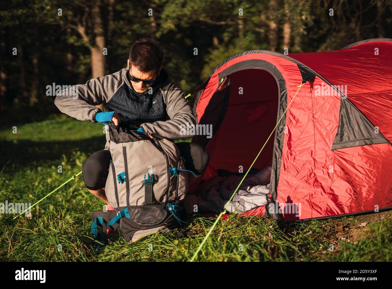 Man camping in Estonia, searching his backpack Stock Photo - Alamy