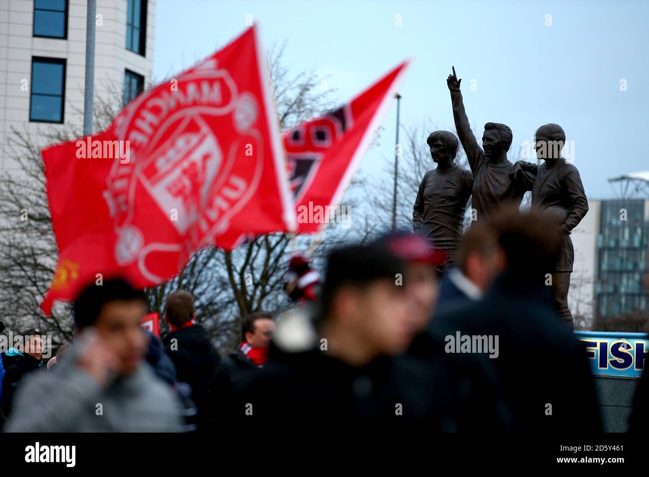 Fans outside the stadium wave flags in front of the statue of Sir Bobby ...