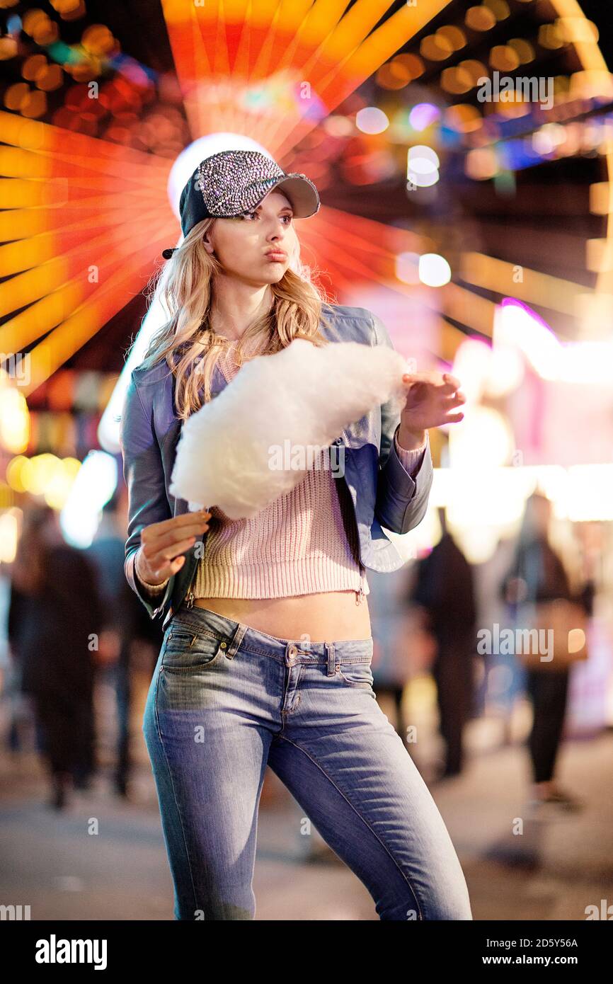 Young woman at fun fair eating candy floss Stock Photo - Alamy