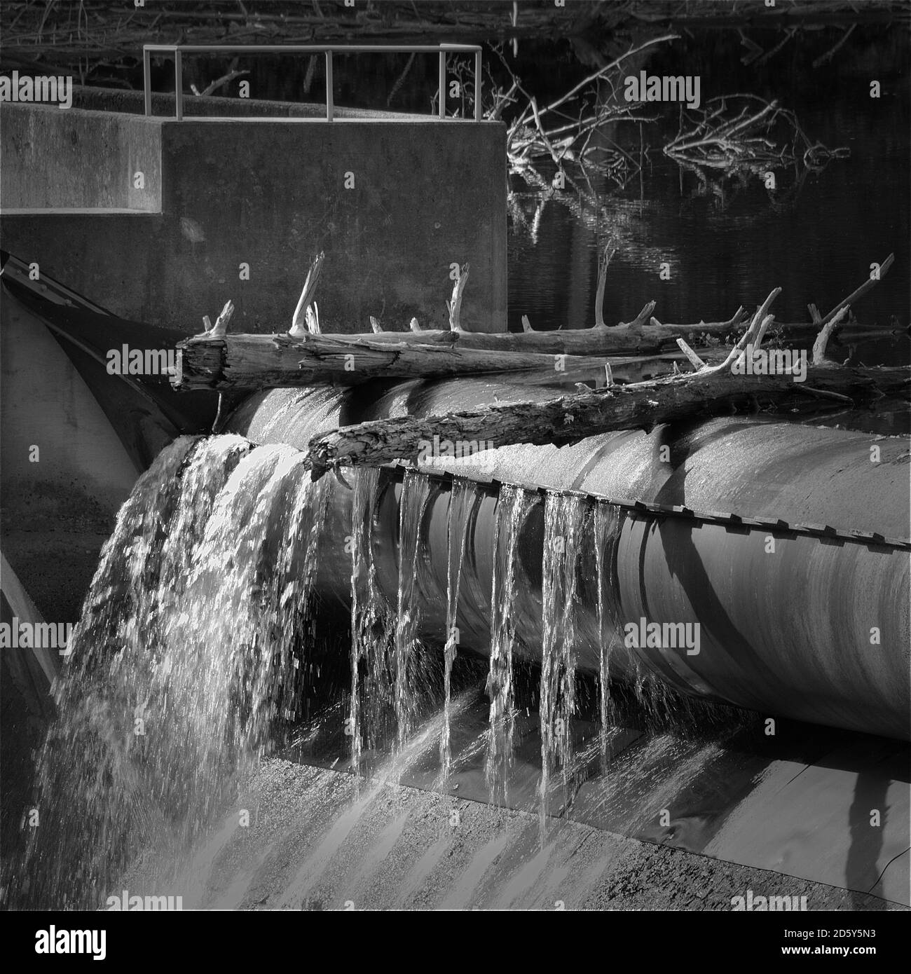 a black & white image depicting logs going over a dam Stock Photo - Alamy