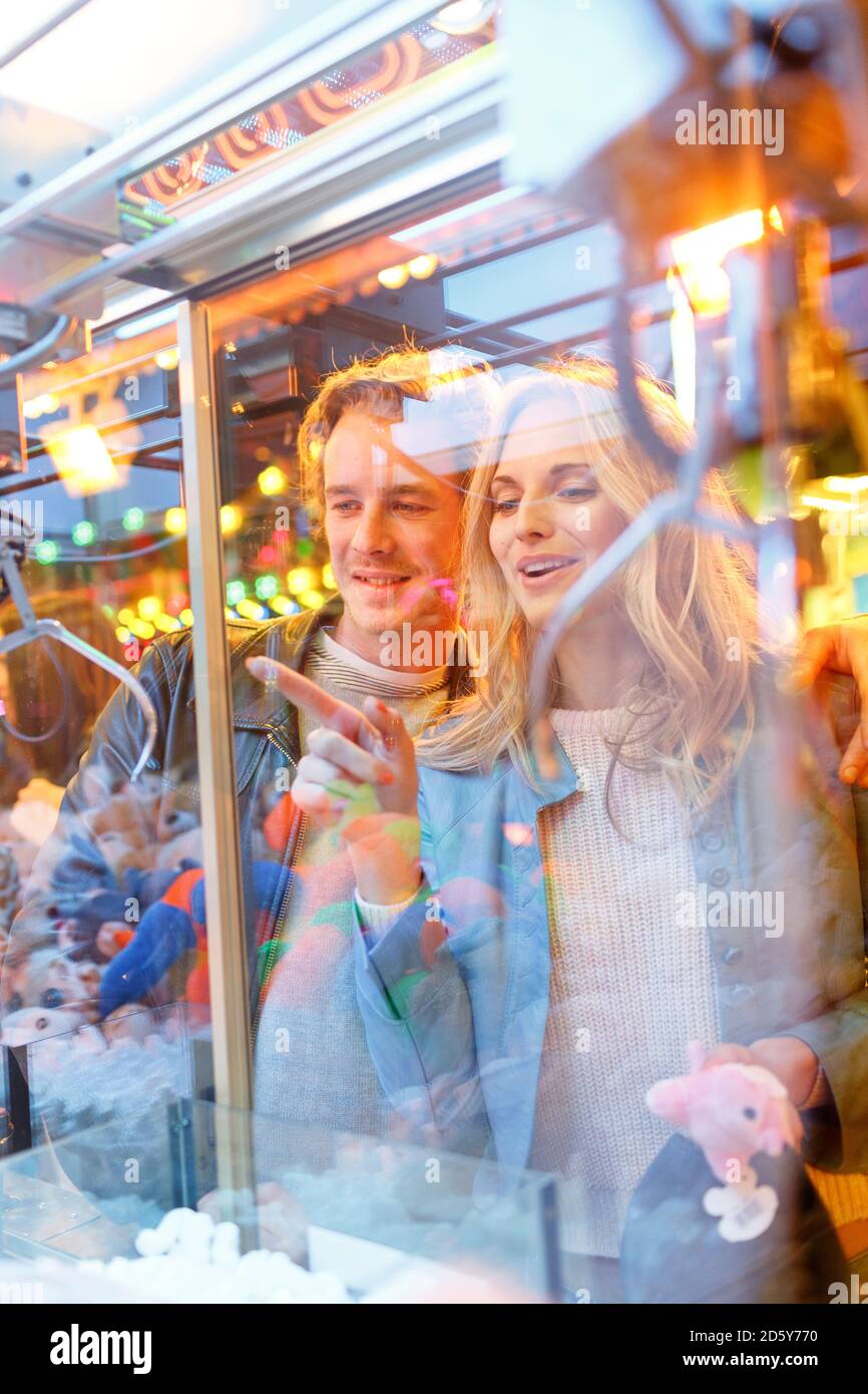 Young couple at fun fair looking at prizes in window Stock Photo - Alamy