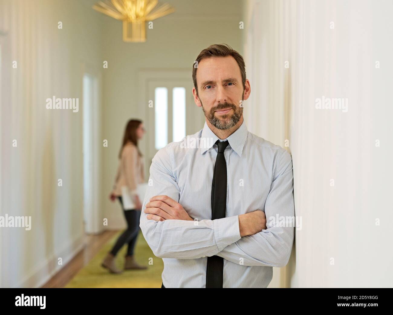 Portrait of businessman leaning against the wall on office floor Stock ...