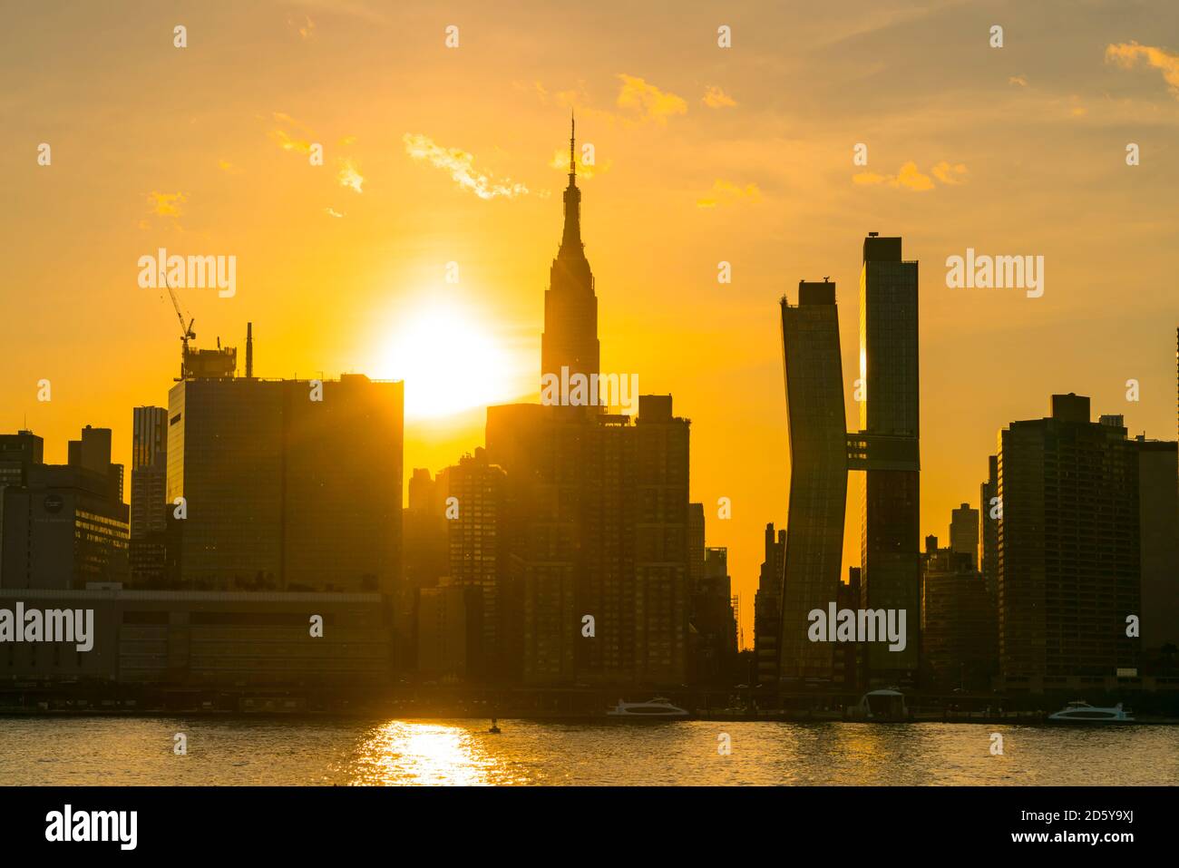 The sun sets to Manhattan skyscraper beyond the East River Stock Photo ...