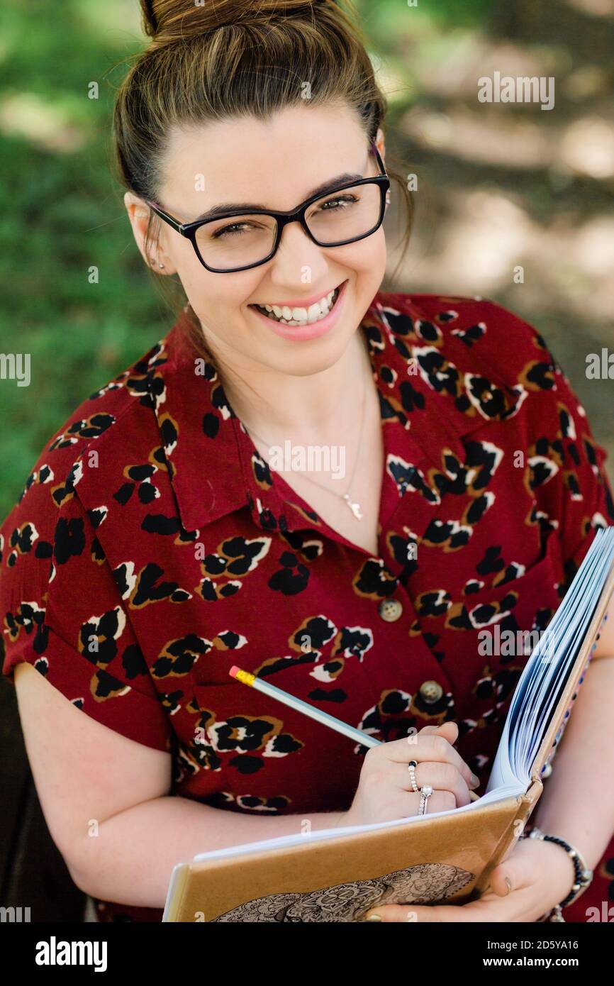 Portrait of laughing woman writing in notebook Stock Photo - Alamy
