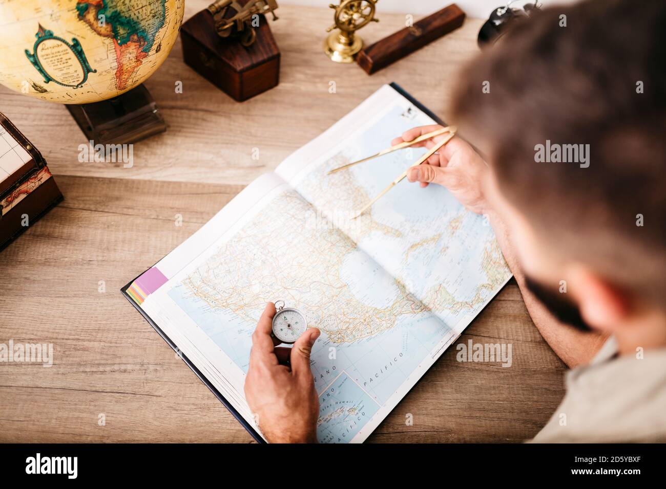 Young man planning journey using compasses Stock Photo - Alamy