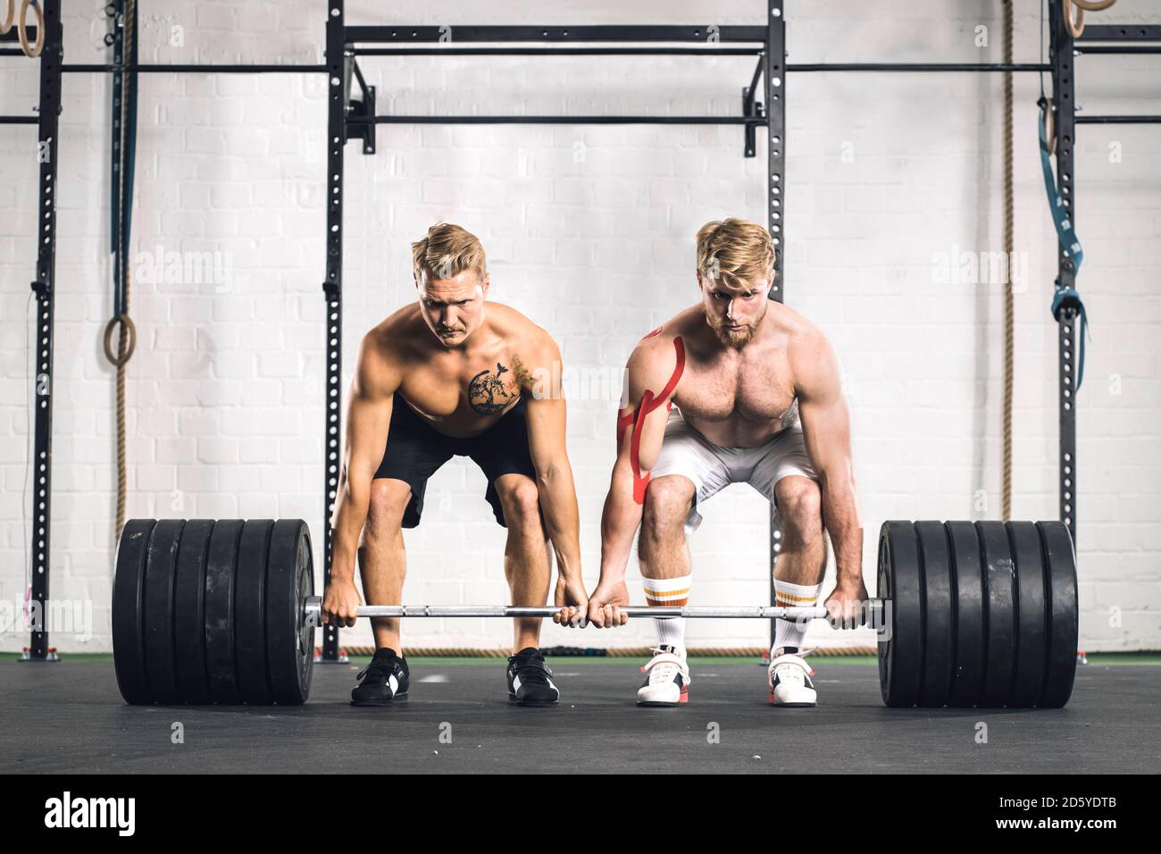 Two young men in gym lifting weights Stock Photo - Alamy
