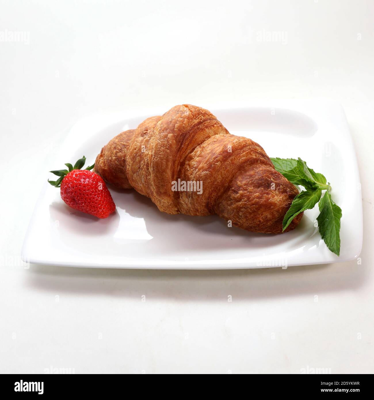 Closeup of a fresh croissant on a plate isolated on a white background ...
