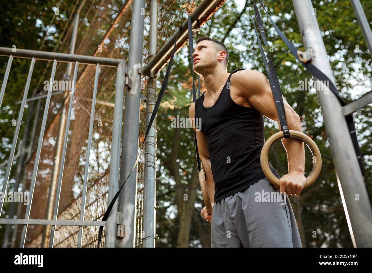Muscly young man training on gymnastic rings Stock Photo - Alamy