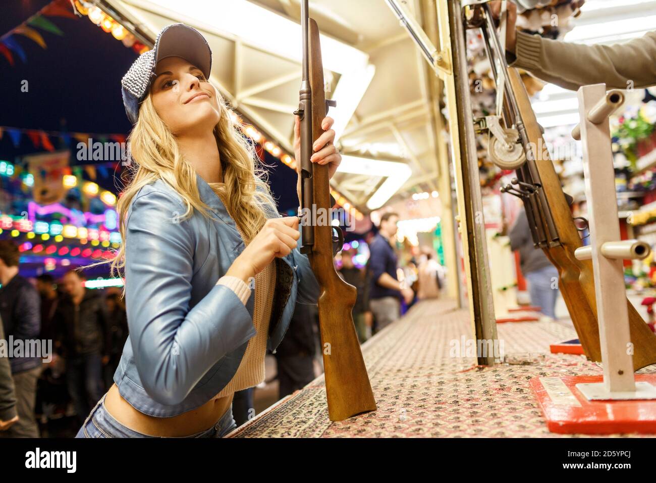 Young woman at fun fair shooting at shooting gallery Stock Photo - Alamy