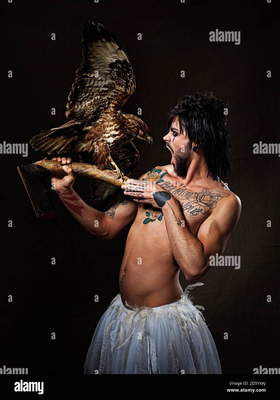 Shirtless man with full beard and eye make up wearing totu holding ...