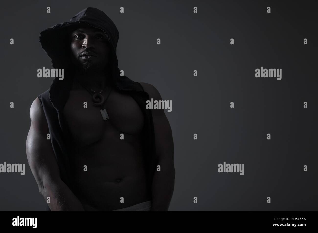 Portrait of muscular man wearing hood in front of dark background Stock ...