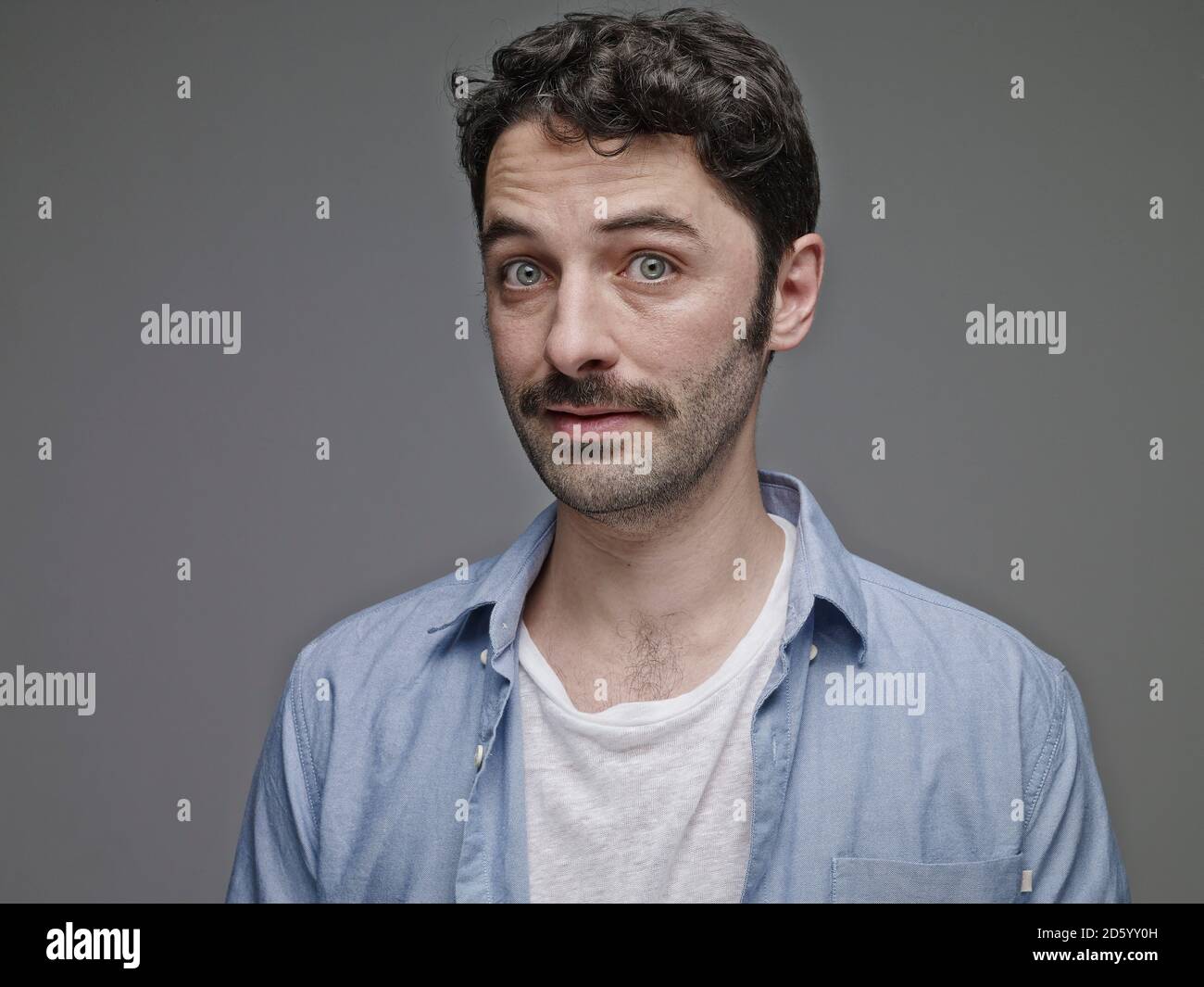 Portrait of sceptical man in front of grey background Stock Photo - Alamy