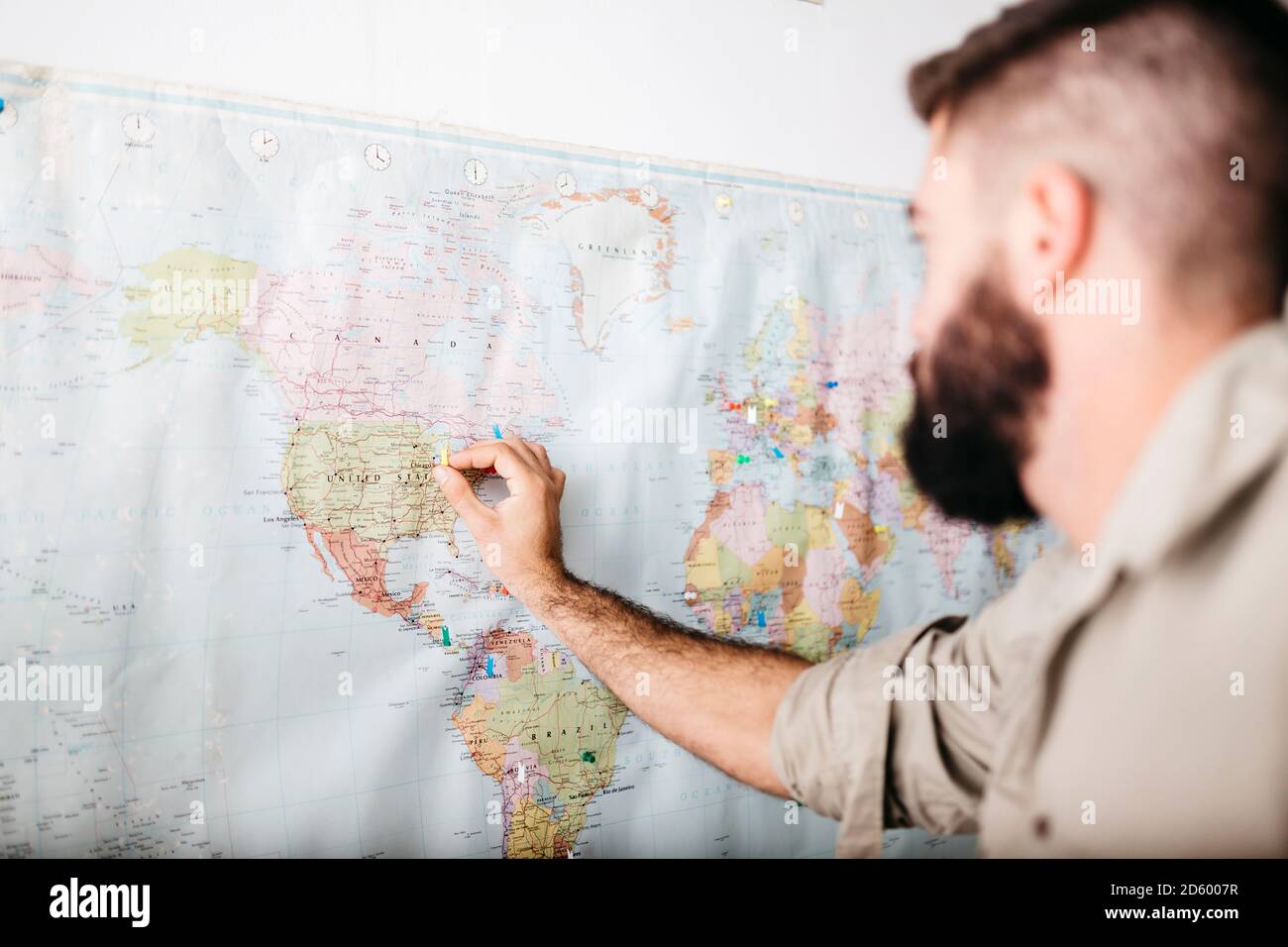 Young man selecting travel destinations on a world map Stock Photo - Alamy