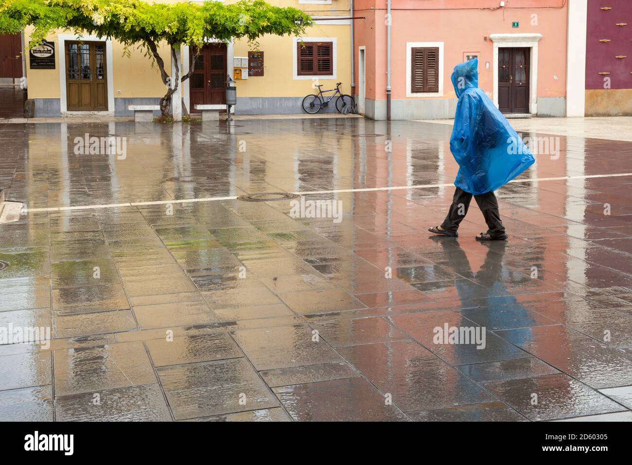 Woman with rain cape crossing carpaccio square hi-res stock photography ...