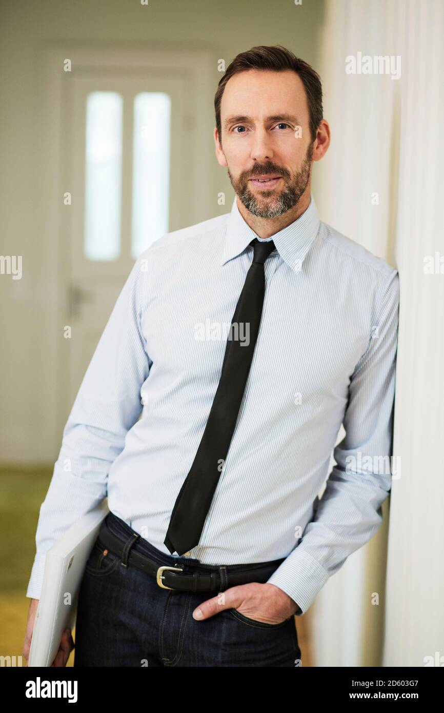 Portrait of businessman leaning against the wall on office floor Stock ...