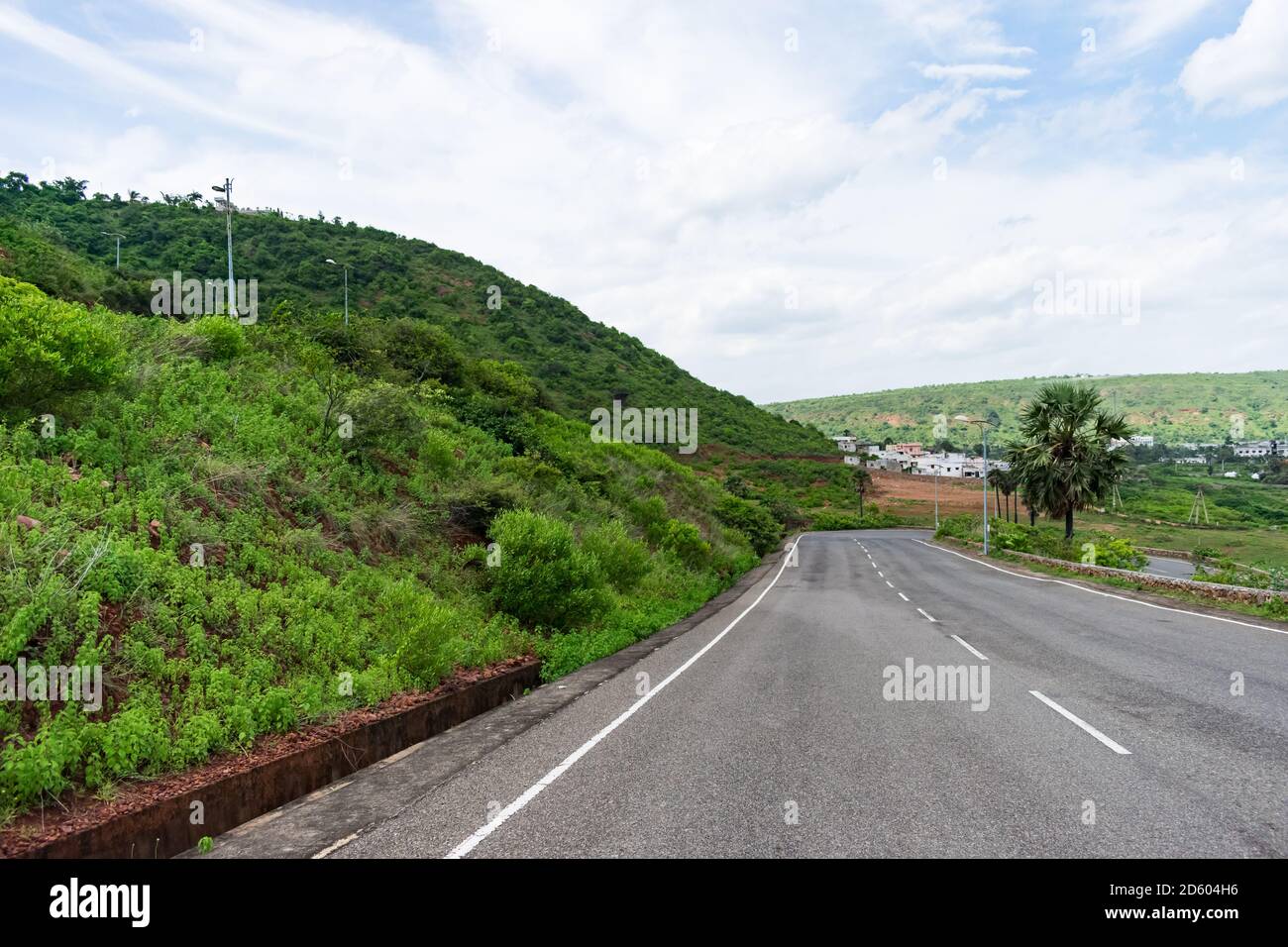 straight road going to downwards down of a mountain with blue ocean ...