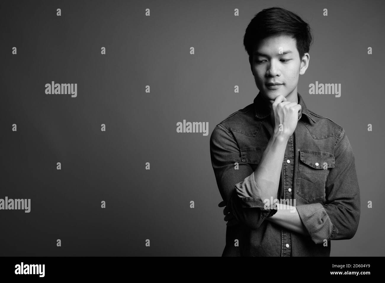 Young Handsome Asian Man Wearing Denim Shirt Against Gray Background