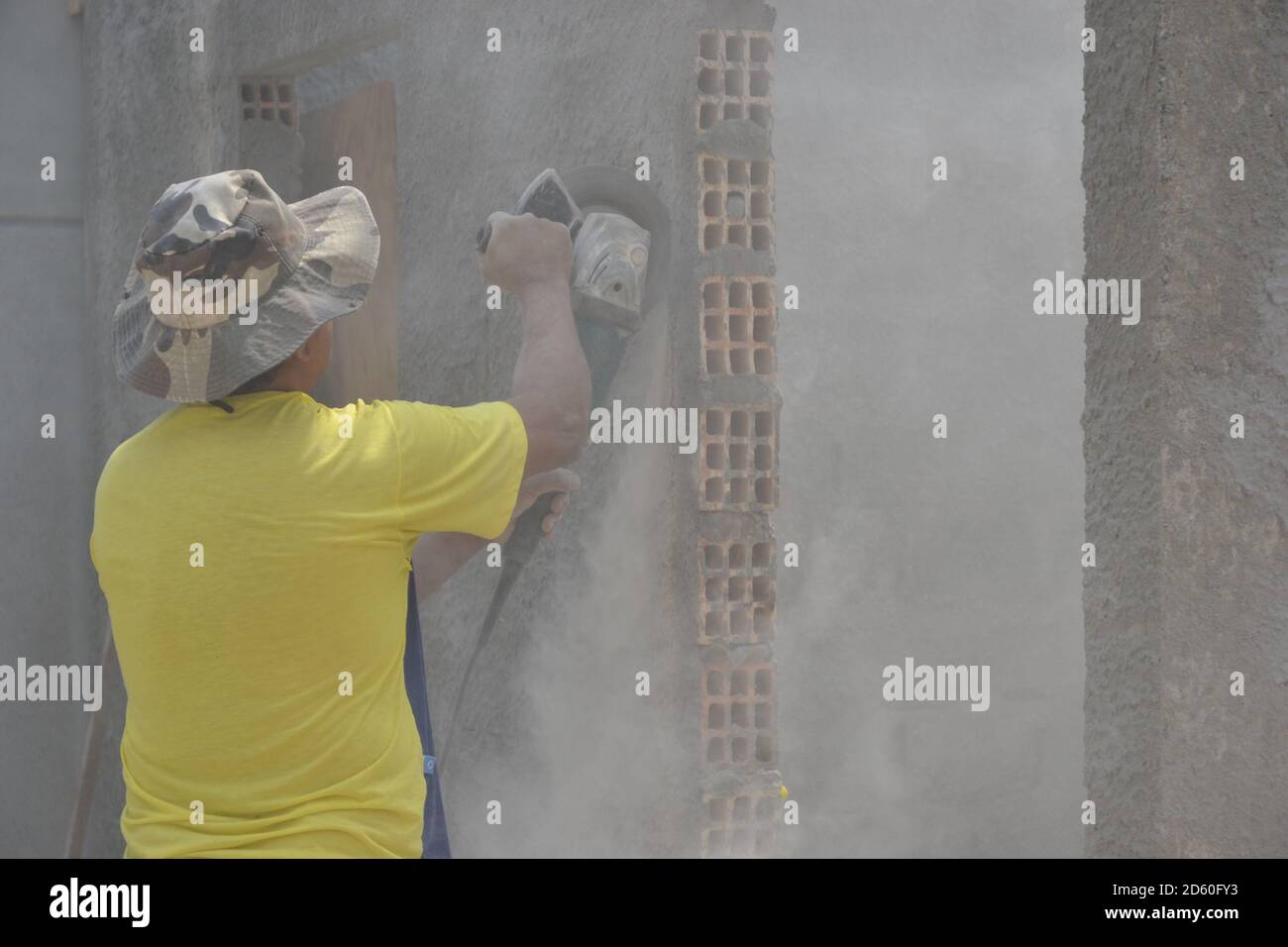 Worker or bricklayer, cutting wall with machine by hand, without ...