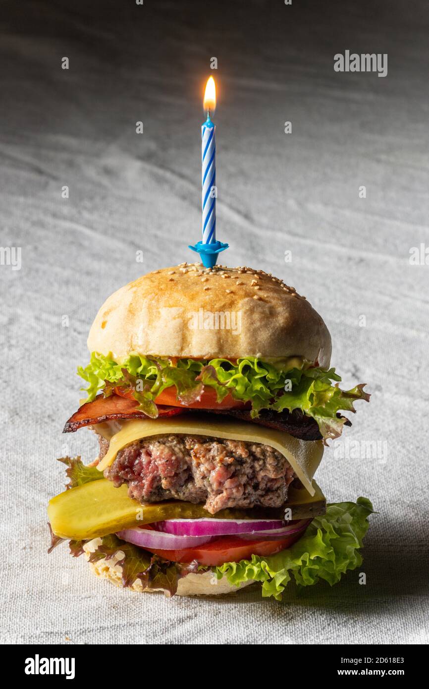 single cheeseburger with a burning candle Stock Photo - Alamy