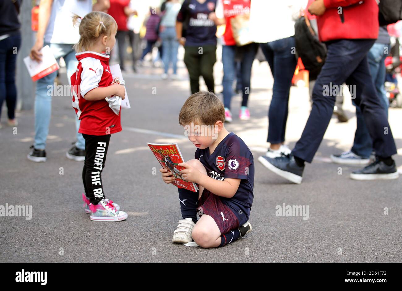 A young Arsenal fan with a match programme outside the ground Stock ...