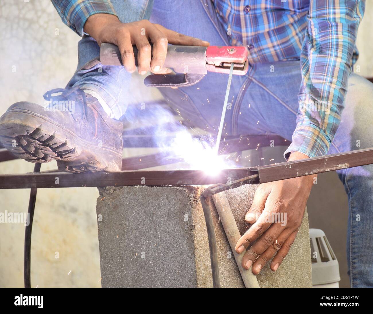An Indian metal welder welding an iron pipe with his welding machine ...