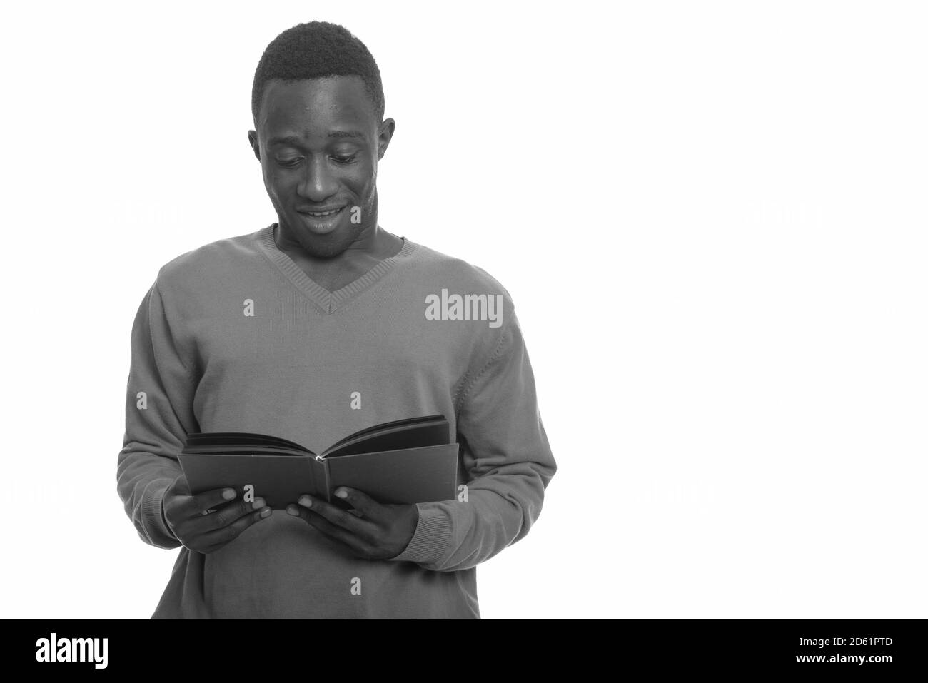 Young happy African man smiling and reading book Stock Photo - Alamy