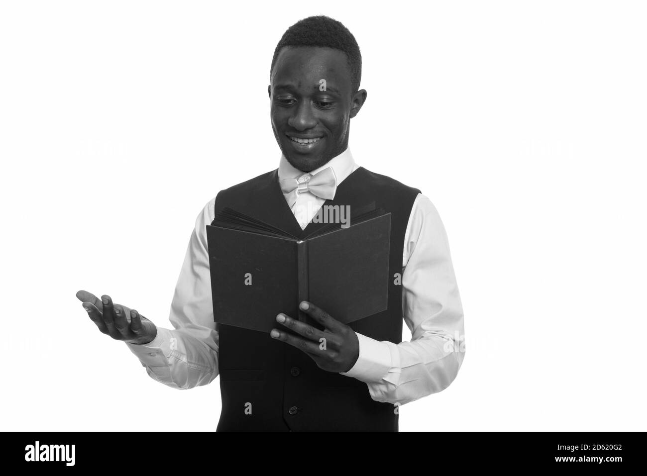 Young happy African waiter smiling and reading book Stock Photo - Alamy