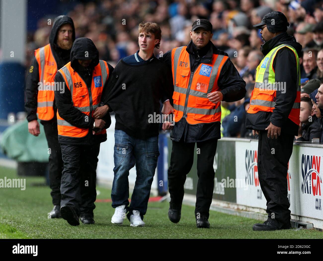 A fan escorted after invading the pitch during the game Stock Photo - Alamy