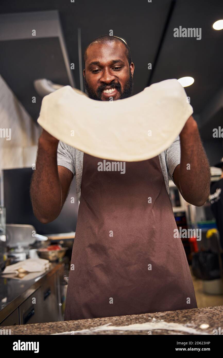 Joyful young man cooking pizza in restaurant Stock Photo - Alamy