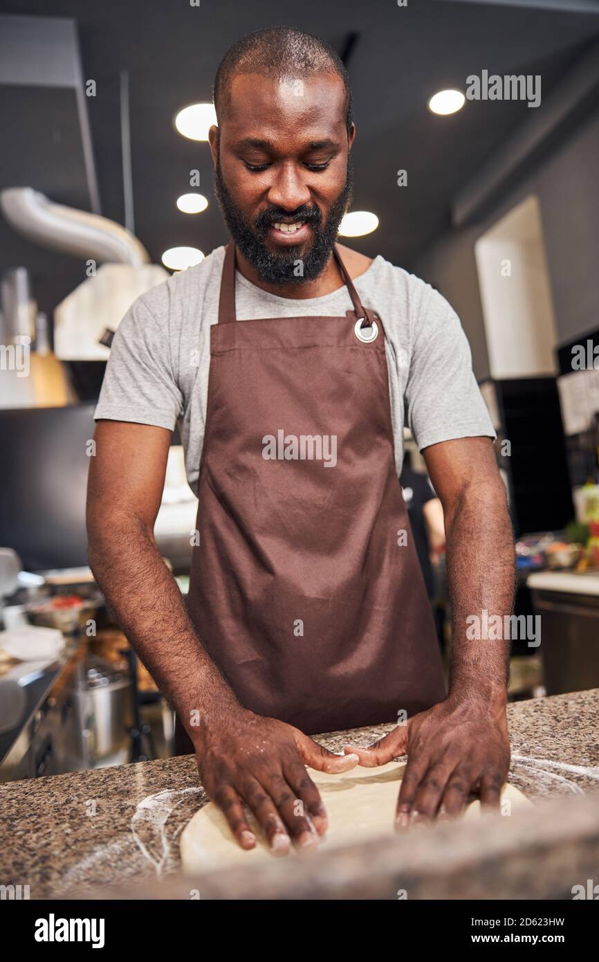 Cheerful young man making pizza in cafe Stock Photo - Alamy