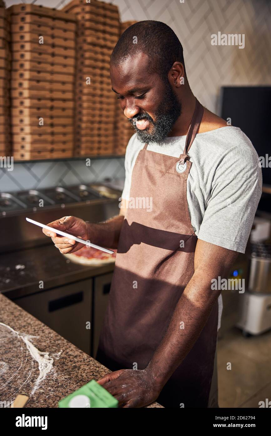 Cheerful young chef using touchpad at work Stock Photo - Alamy
