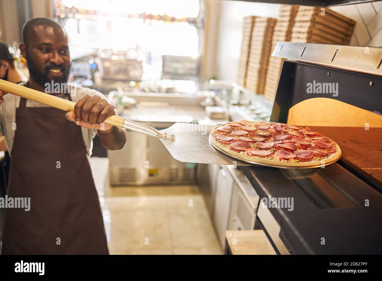 Cheerful young man enjoying work in pizzeria Stock Photo - Alamy