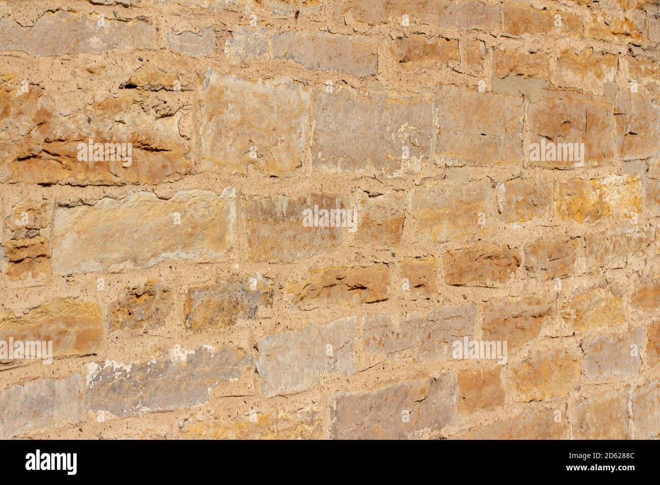 Antique golden brown color stone wall background with worn texture in ...