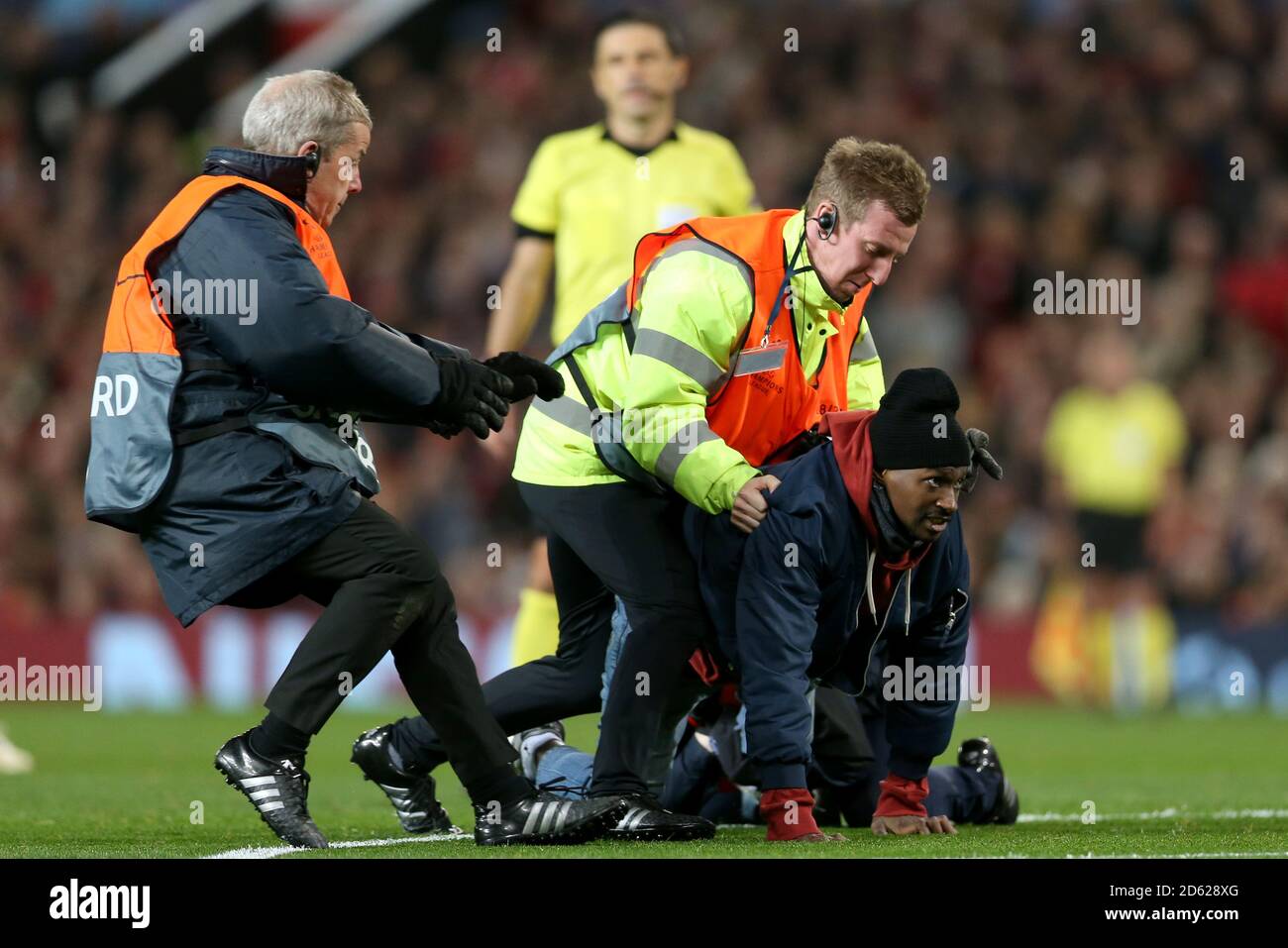 Stewards attempt to remove pitch invaders during the match Stock Photo ...