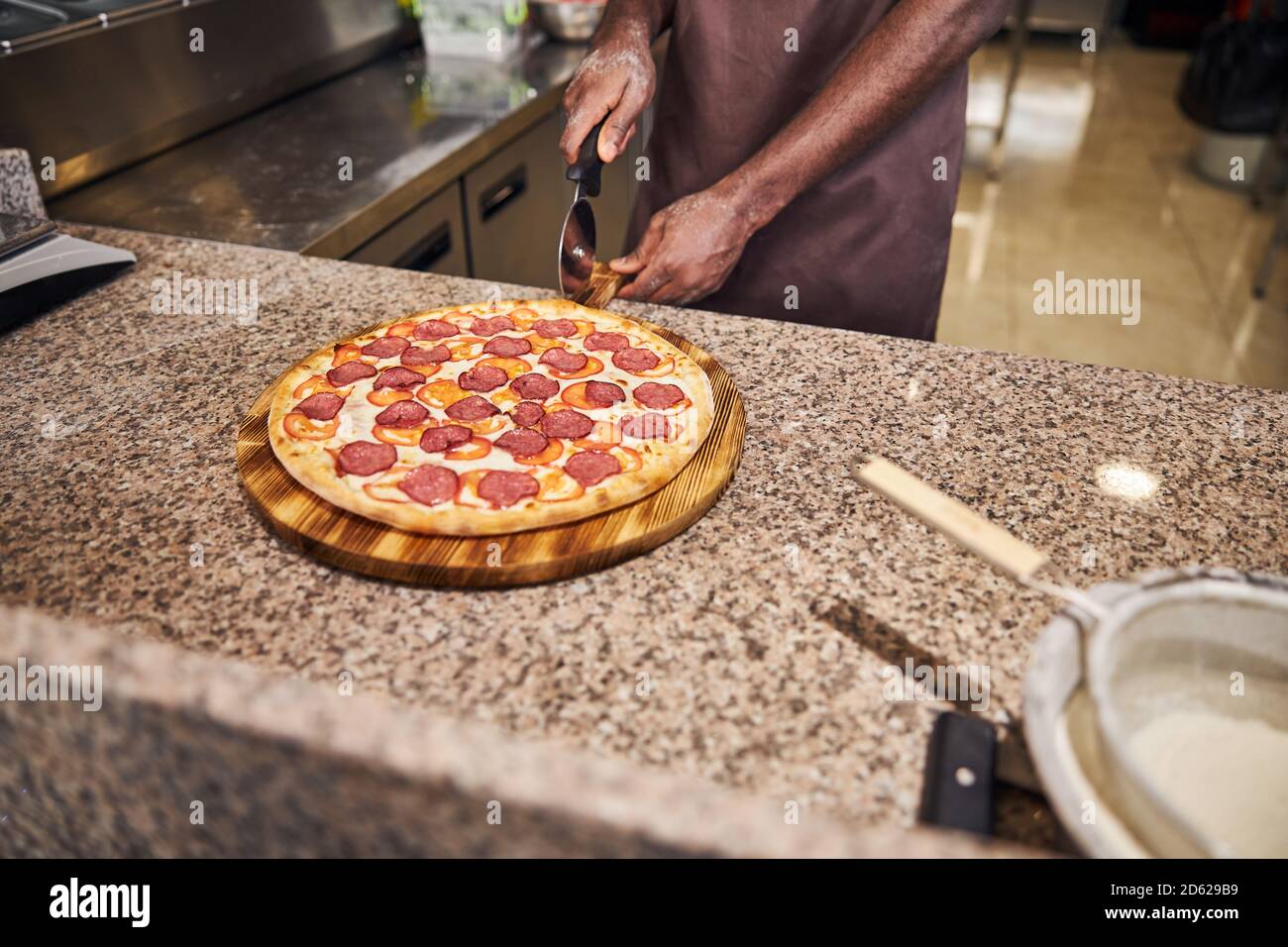 Young man cutting pepperoni pizza in pizzeria Stock Photo - Alamy