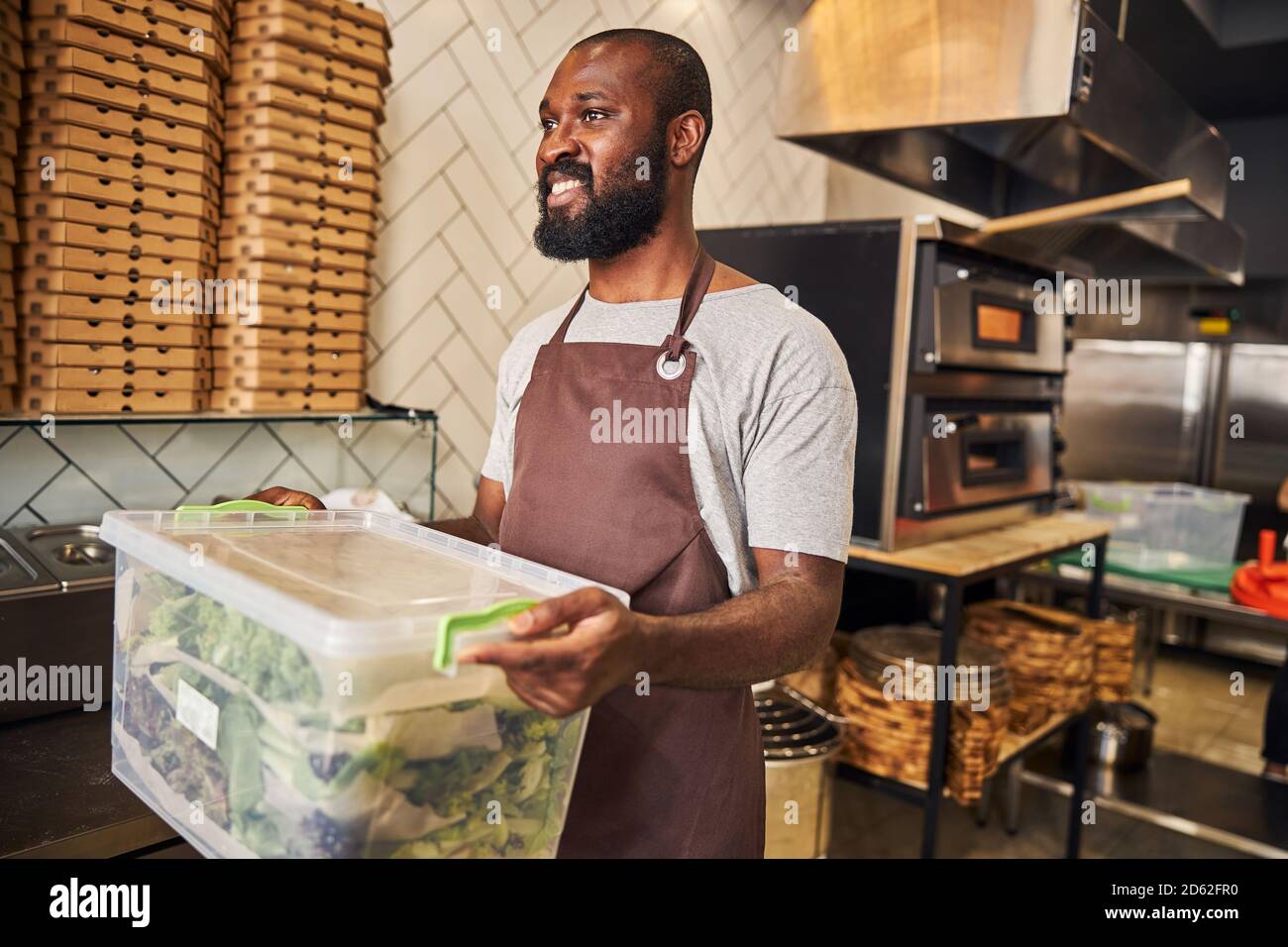 Cheerful male worker holding container with leafy greens Stock Photo ...