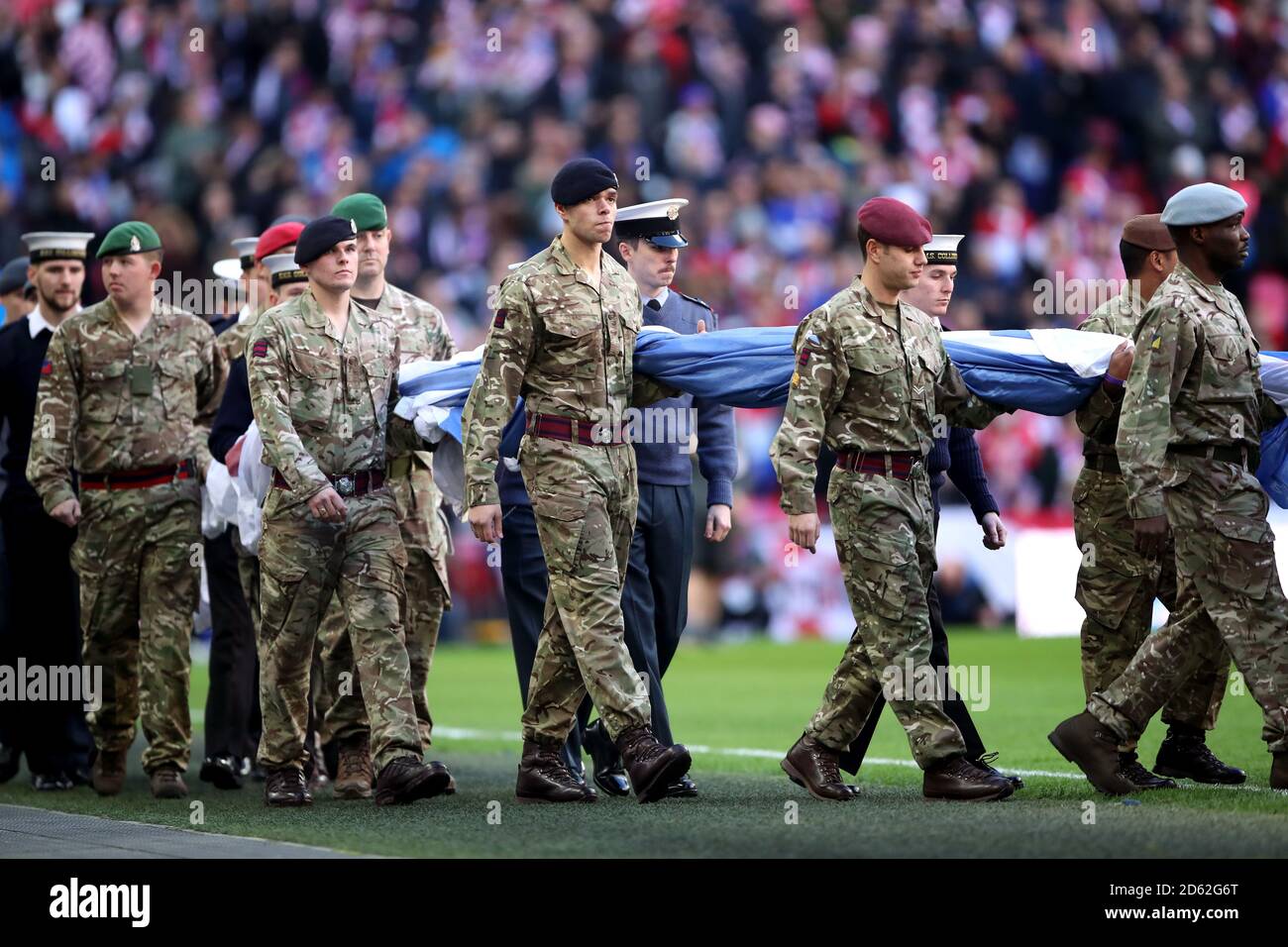 Members of the armed forces carry a giant flag onto the pitch before ...
