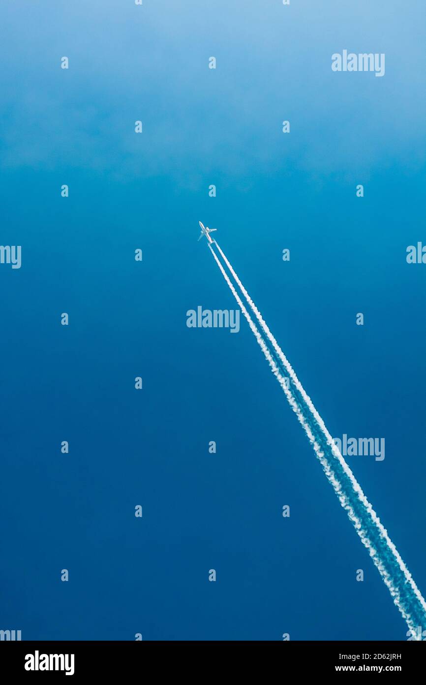 Airplane In Sky With Plane Trails Stock Photo - Alamy