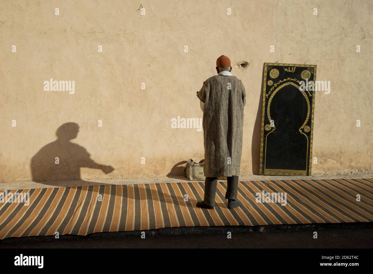 Muslim man praying by city walls in the afternoon in Marrakesh, Morocco ...