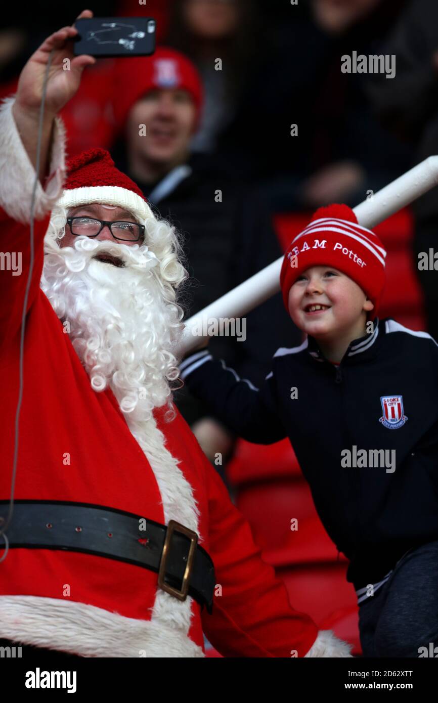 A Stoke City fan dressed as santa take a selfie with young fan prior to ...