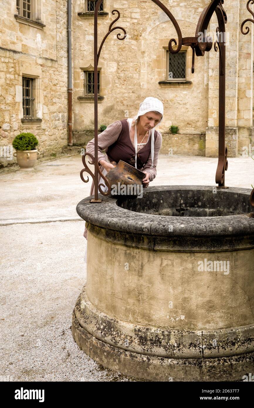 Woman in historic outfit working at an old water well of a French ...